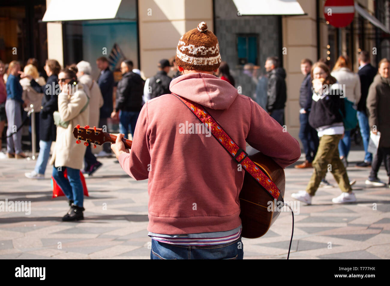 Street musician playing guitar in busy walking street with people ...