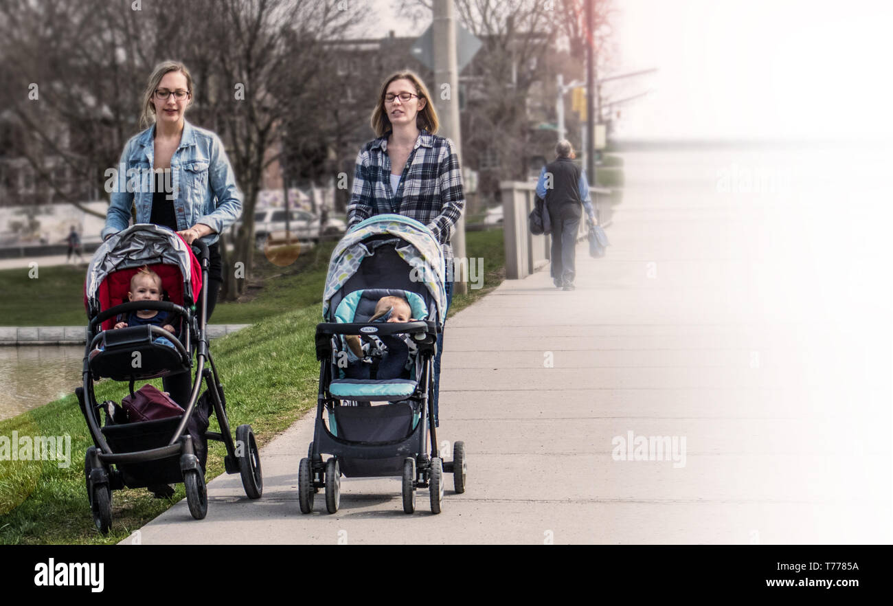 Two young mothers with their strollers, walk along the boulevard Stock ...