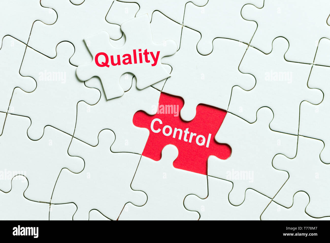 White jigsaw puzzle with a word quality control Stock Photo - Alamy