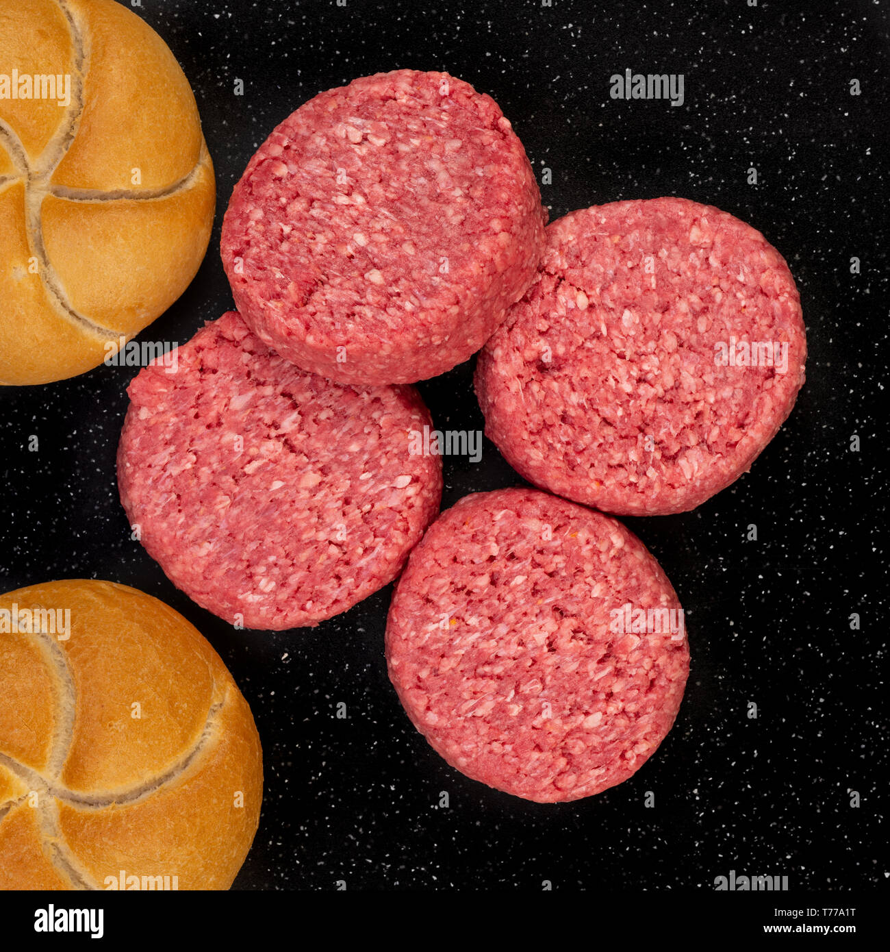 Fresh raw prime black Angus beef burger patties and bread buns on black ...