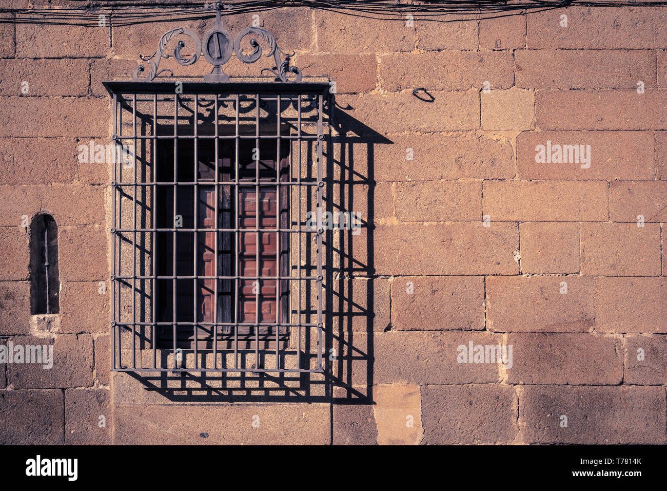 Window with bars on a stone facade in old medieval town of Plasencia ...