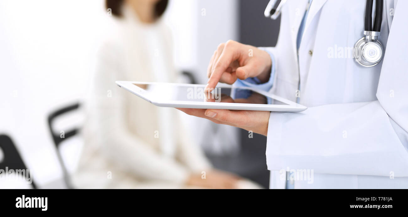 Female physician using digital tablet while standing near reception ...