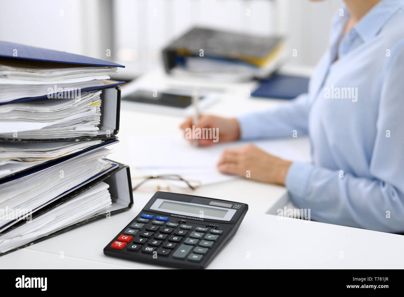Calculator and binders with papers are waiting to be processed by ...