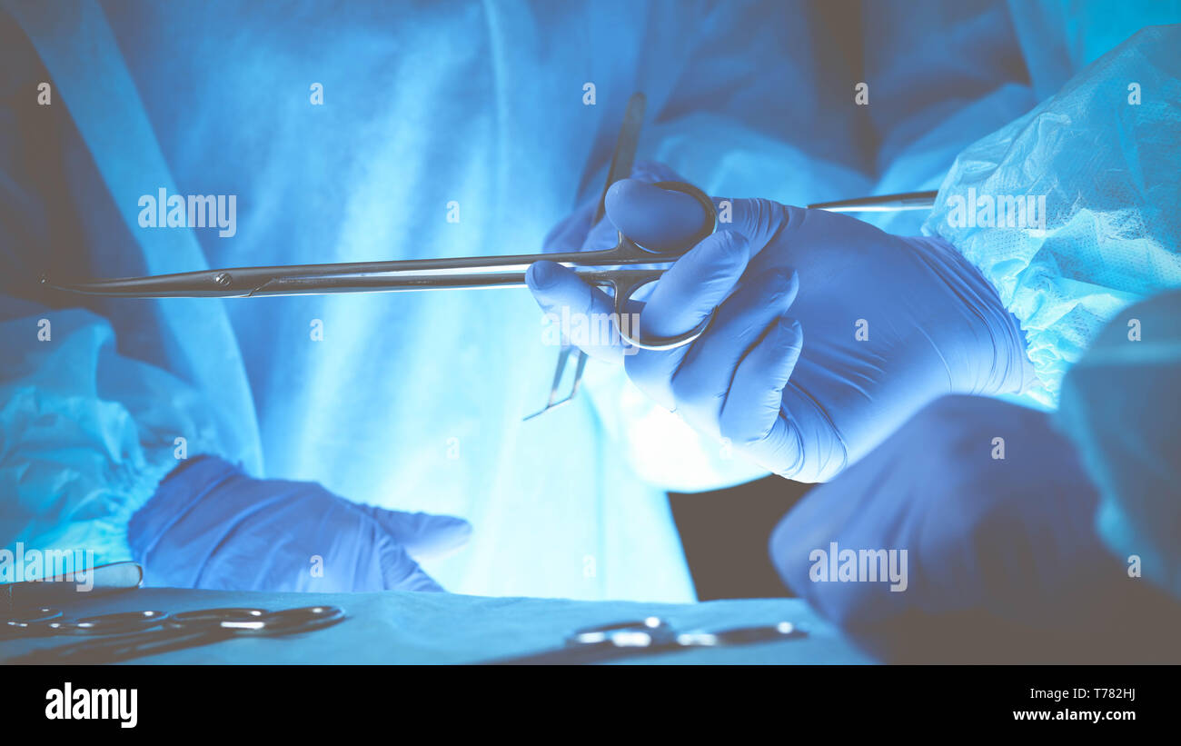 Surgeons hands holding surgical scissors and passing surgical equipment ...