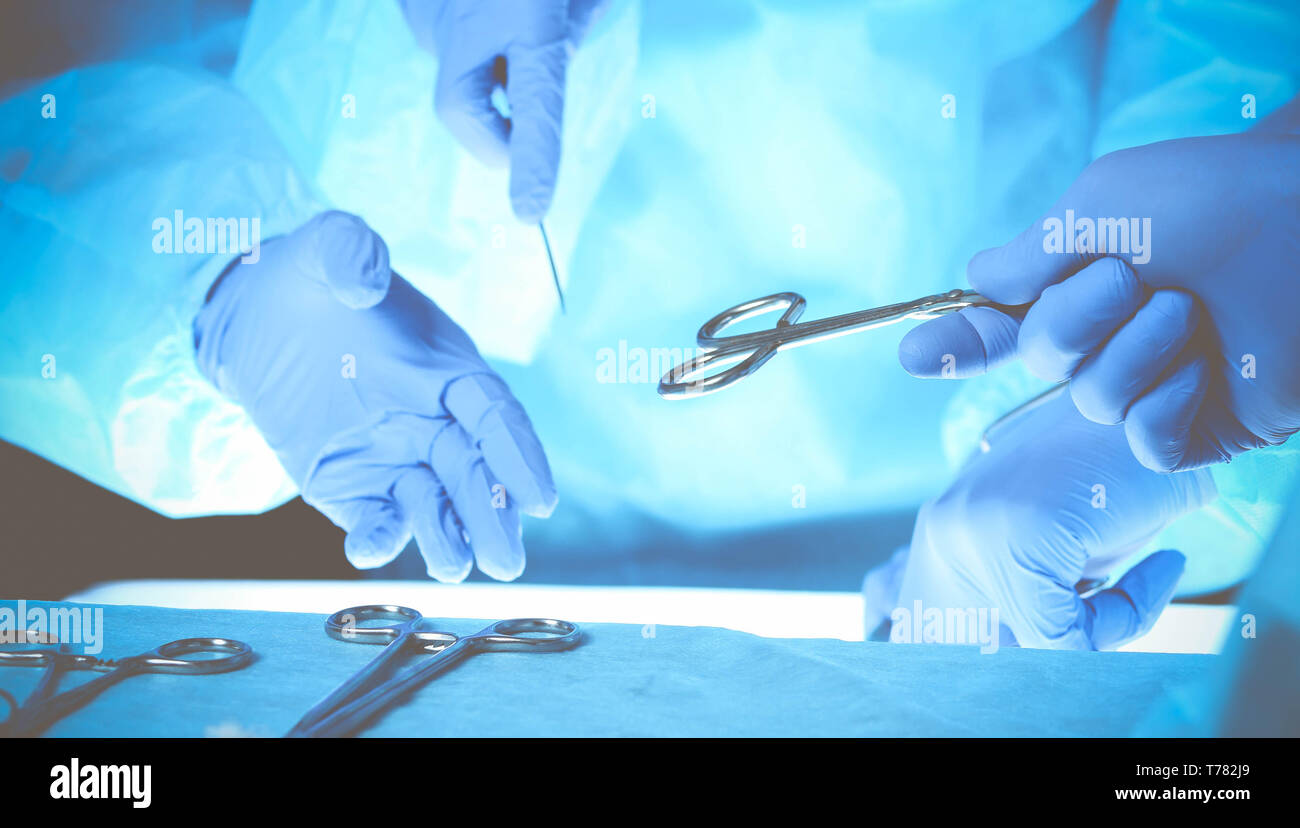 Surgeons hands holding surgical scissors and passing surgical equipment ...