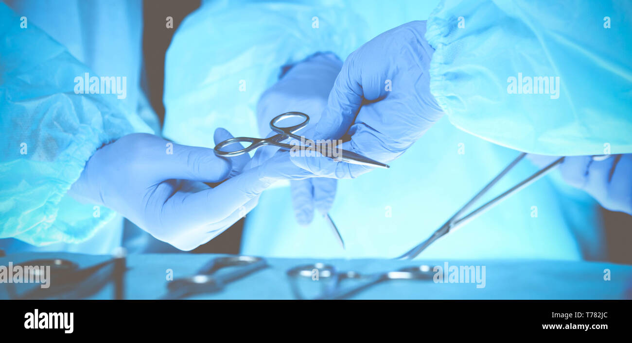 Surgeons hands holding surgical scissors and passing surgical equipment ...