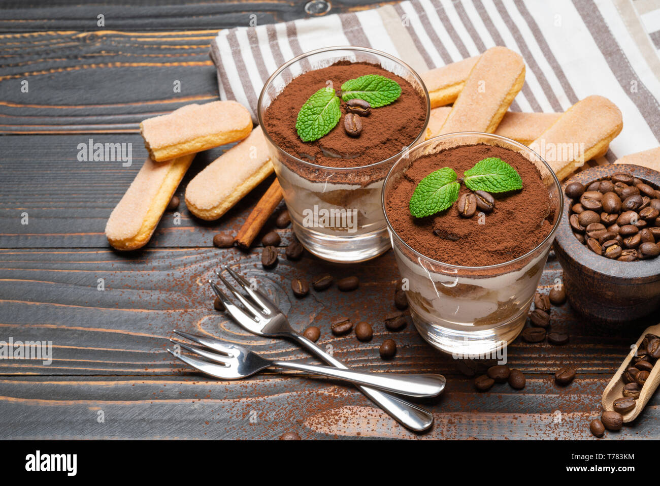 two portions Classic tiramisu dessert in a glass on wooden background ...