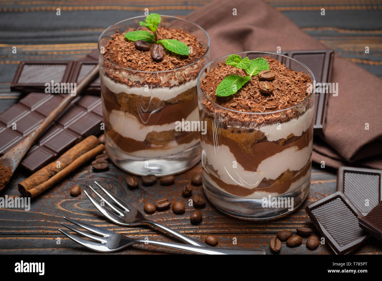 two portions Classic tiramisu dessert in a glass and chocolate bar on ...