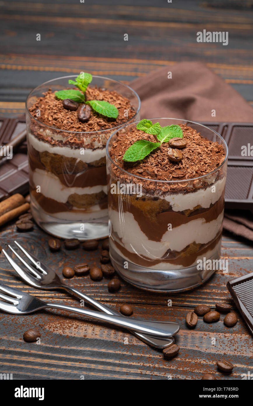 two portions Classic tiramisu dessert in a glass and chocolate bar on ...