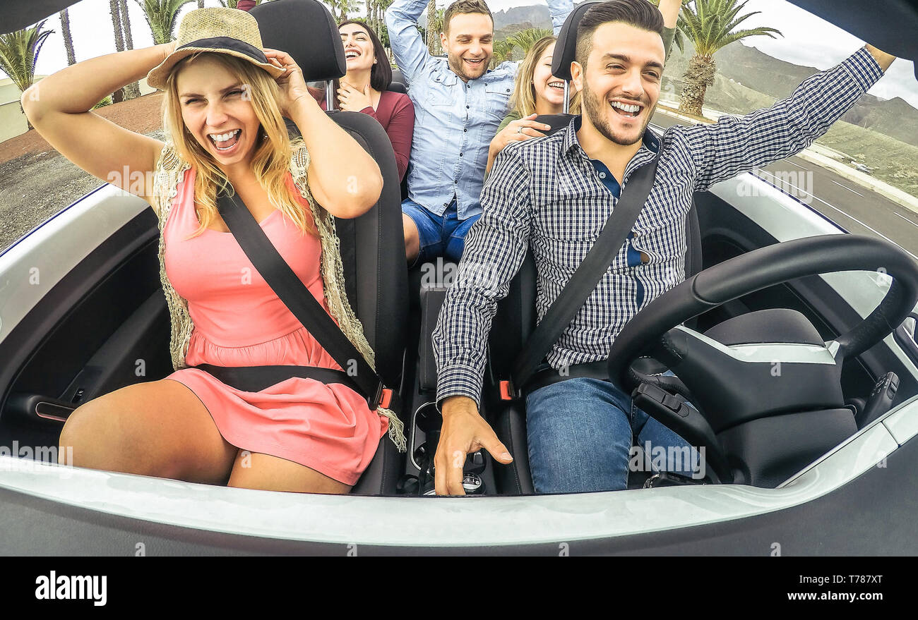 Happy friends having fun and dancing in convertible car in vacation ...
