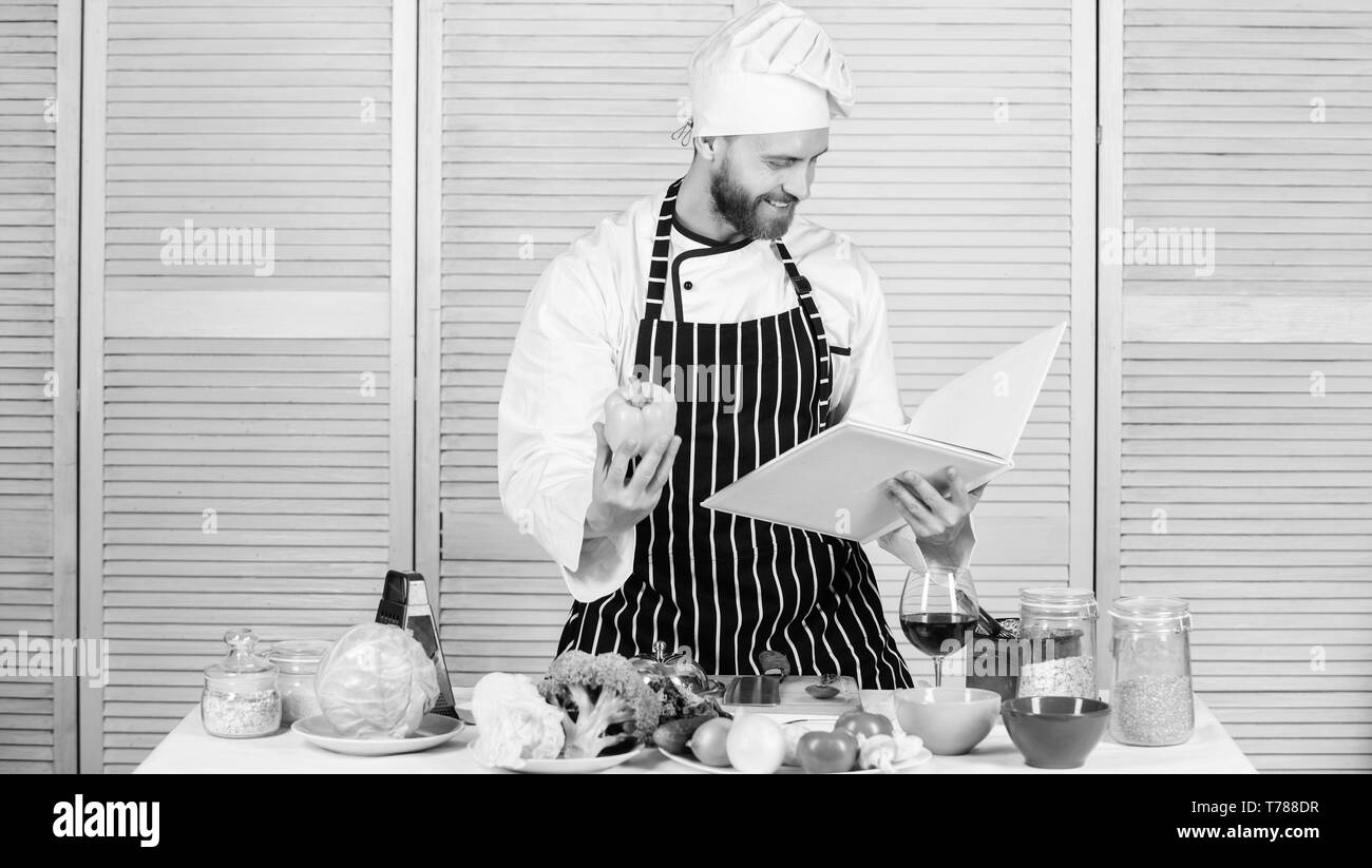 According to recipe. Man bearded chef cooking food. Guy read book ...