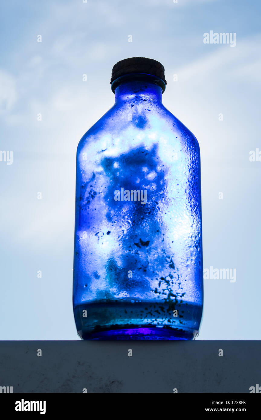 Old antique blue glass bottle backlit by the sun Stock Photo - Alamy