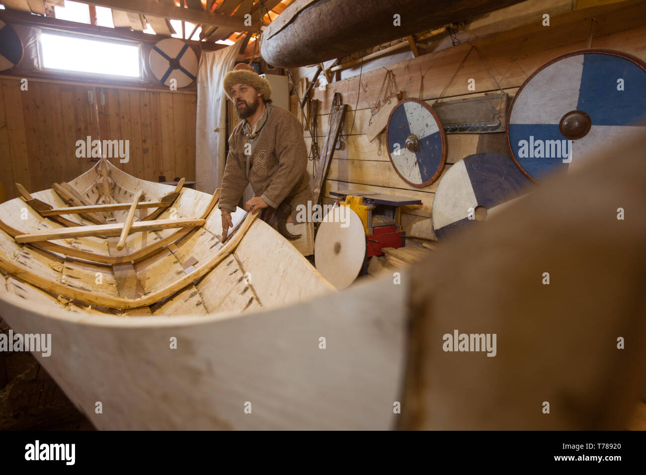 Handmade wooden boat in the barn and reenactor in medieval clothes ...