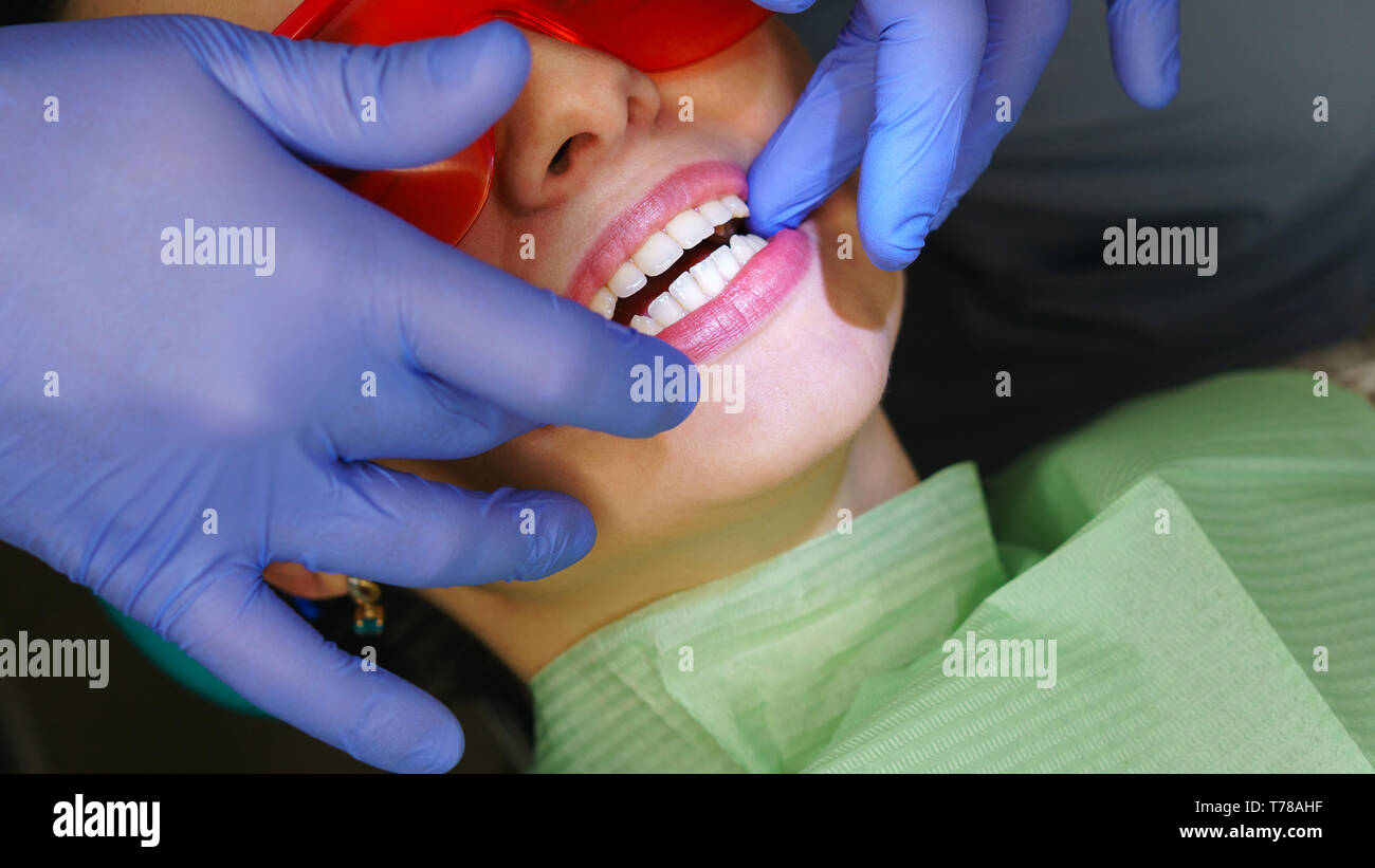 Girl patient in dental clinic. Doctor conducts routine inspection of ...