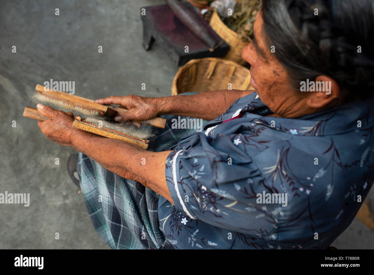 Zapotec woman combing the raw wool using hand carders to prepare wool ...