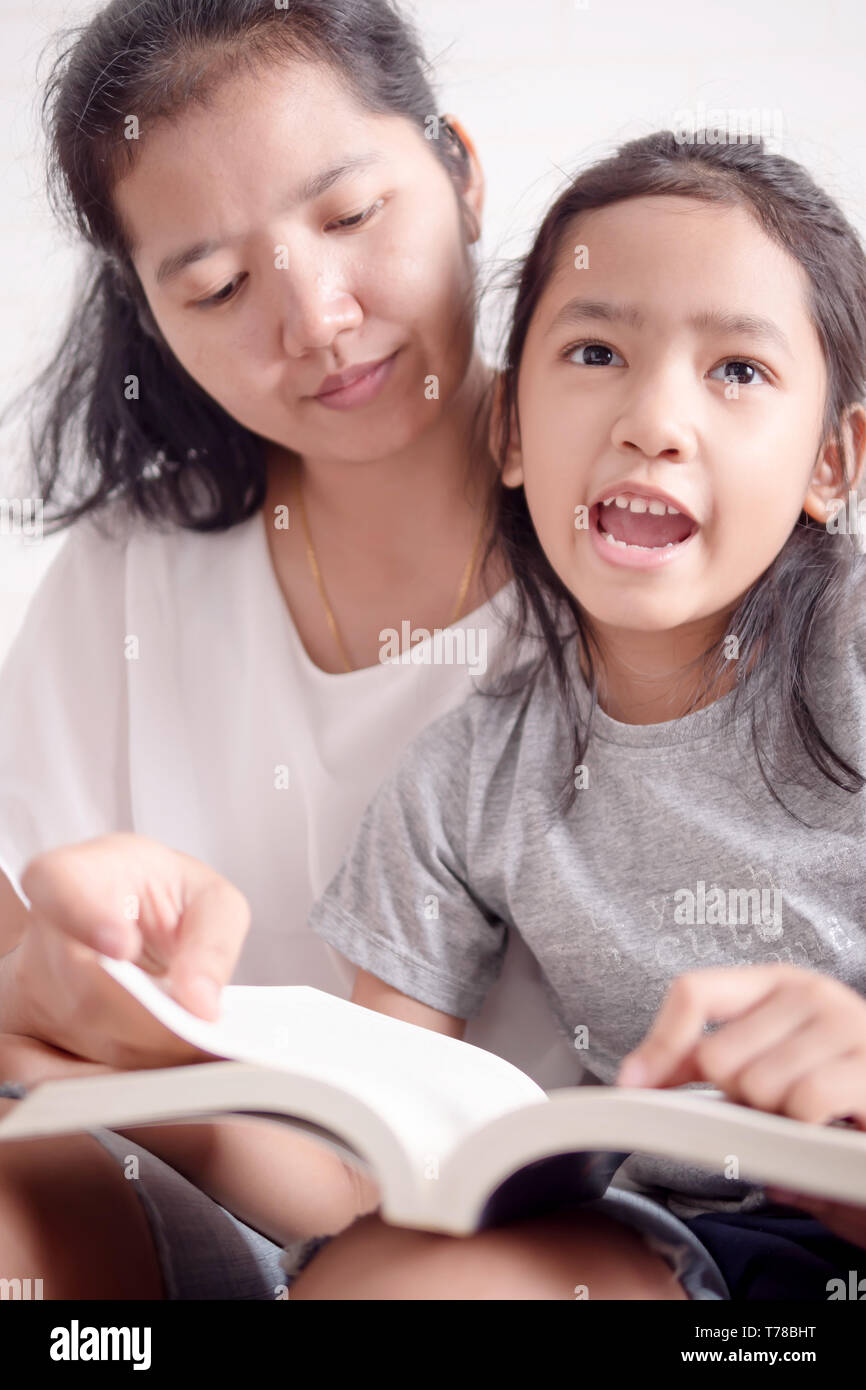 Close up mother and daughter read books together. Women teaching girl ...