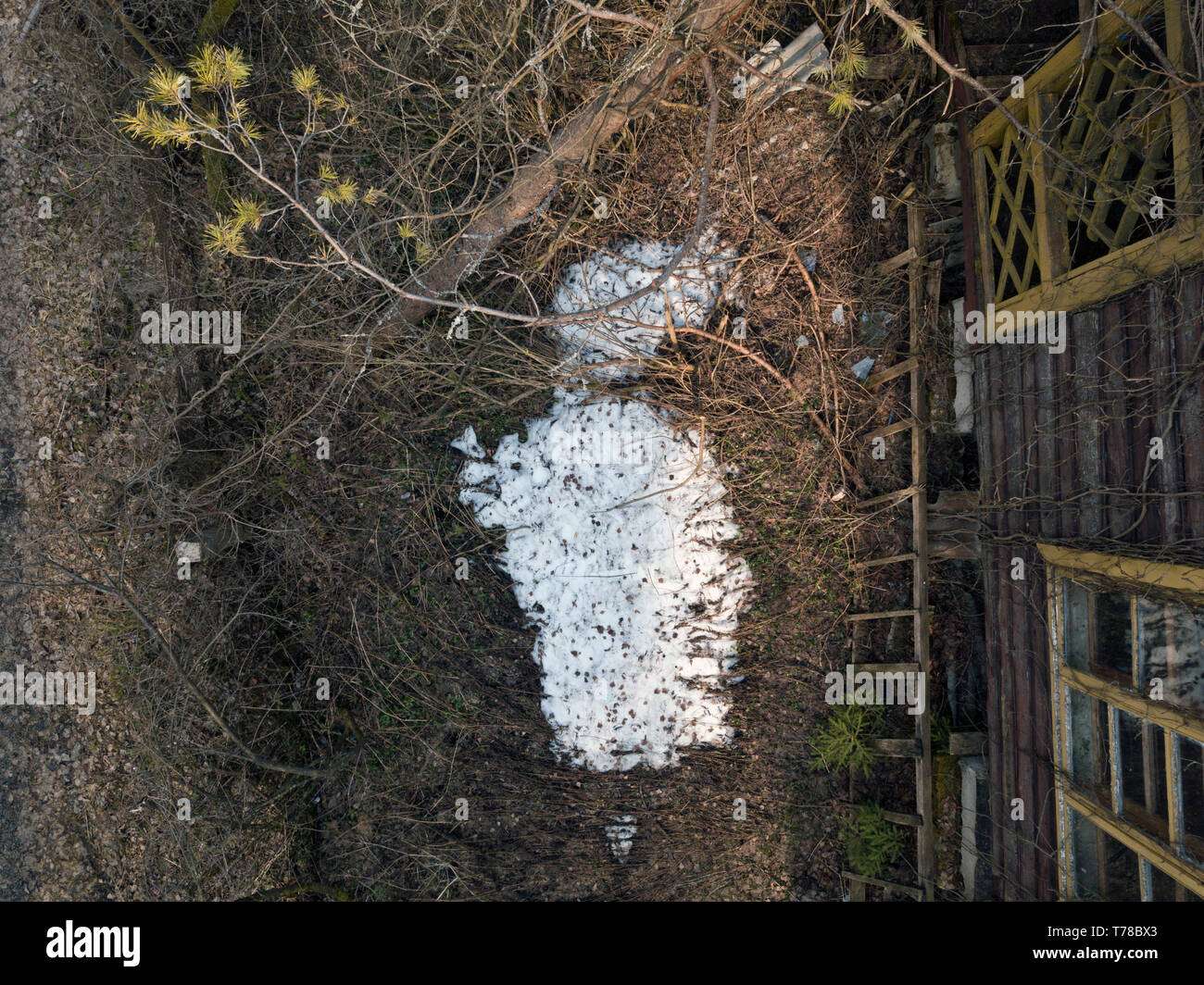 Birds eye view of the last snow on the lawn next to a rural wooden ...
