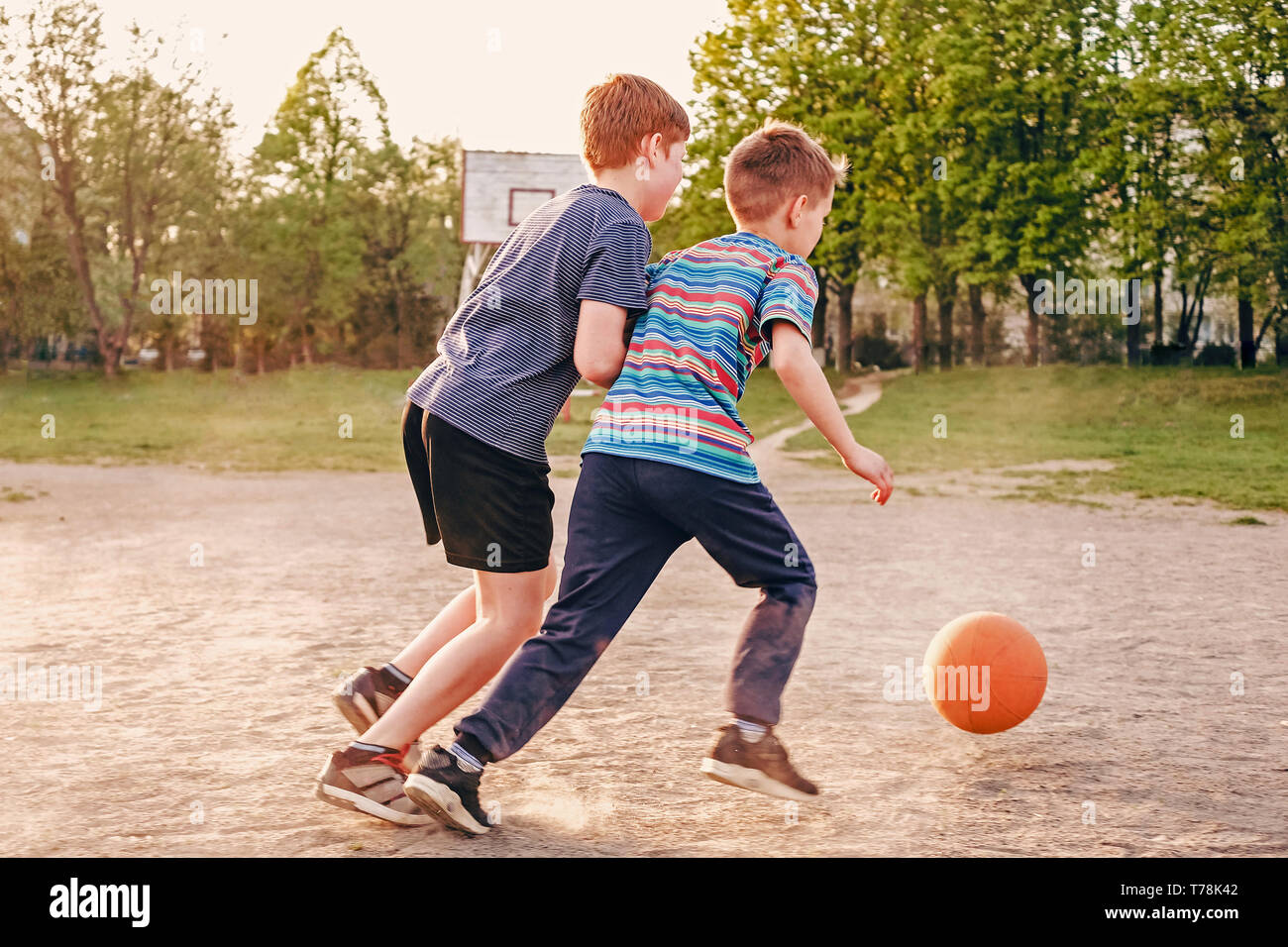 Two young boys chasing a basketball while practicing their game ...