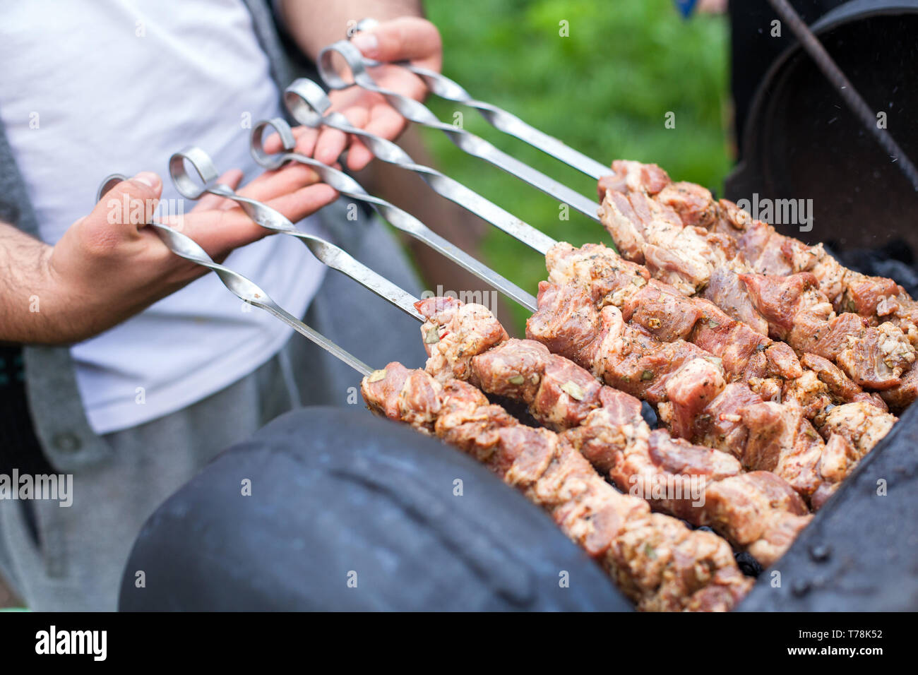 Chief-cooker hand are grilling BBQ at home on an open fire, skewing ...