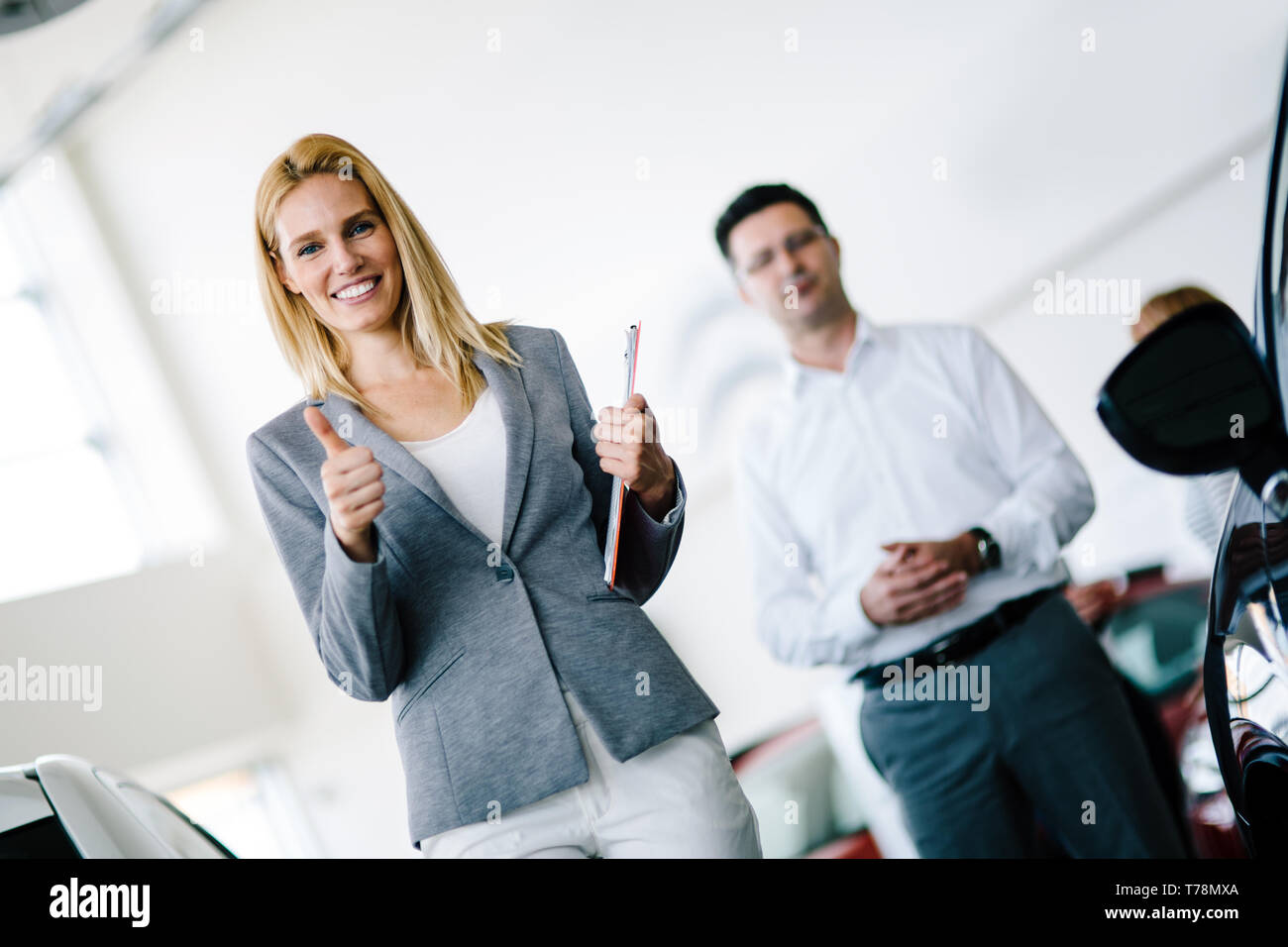 Professional salesperson during work with customer at car dealership ...