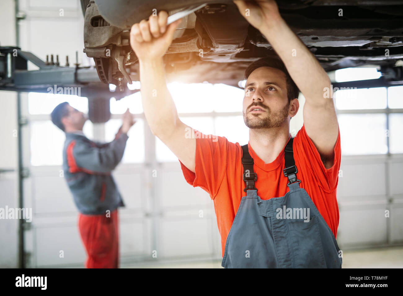 Profecional car mechanic changing motor oil at maintenance repair ...