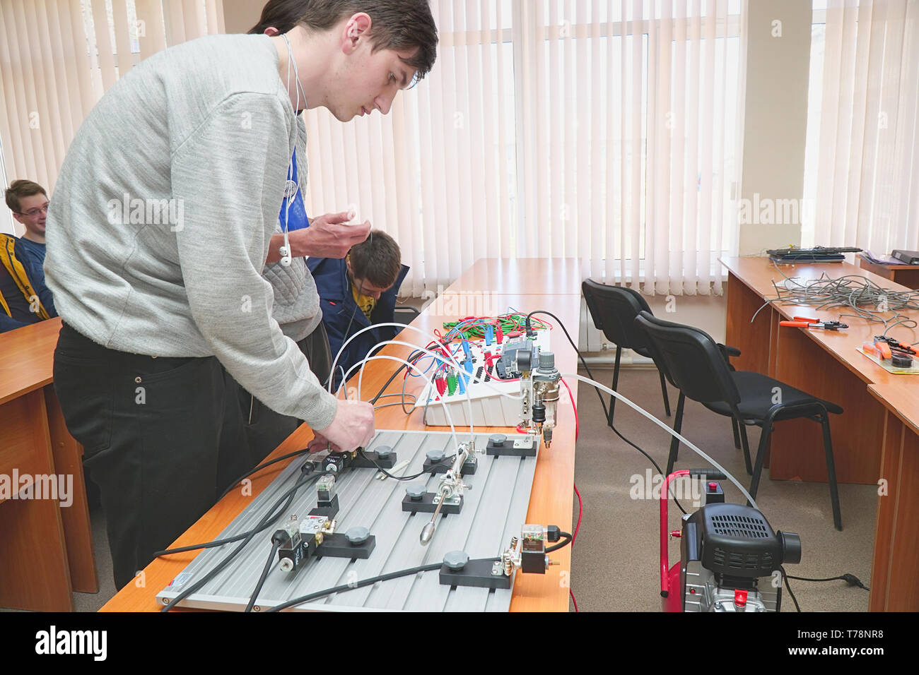 Students connect wires control panel with small test bench for ...