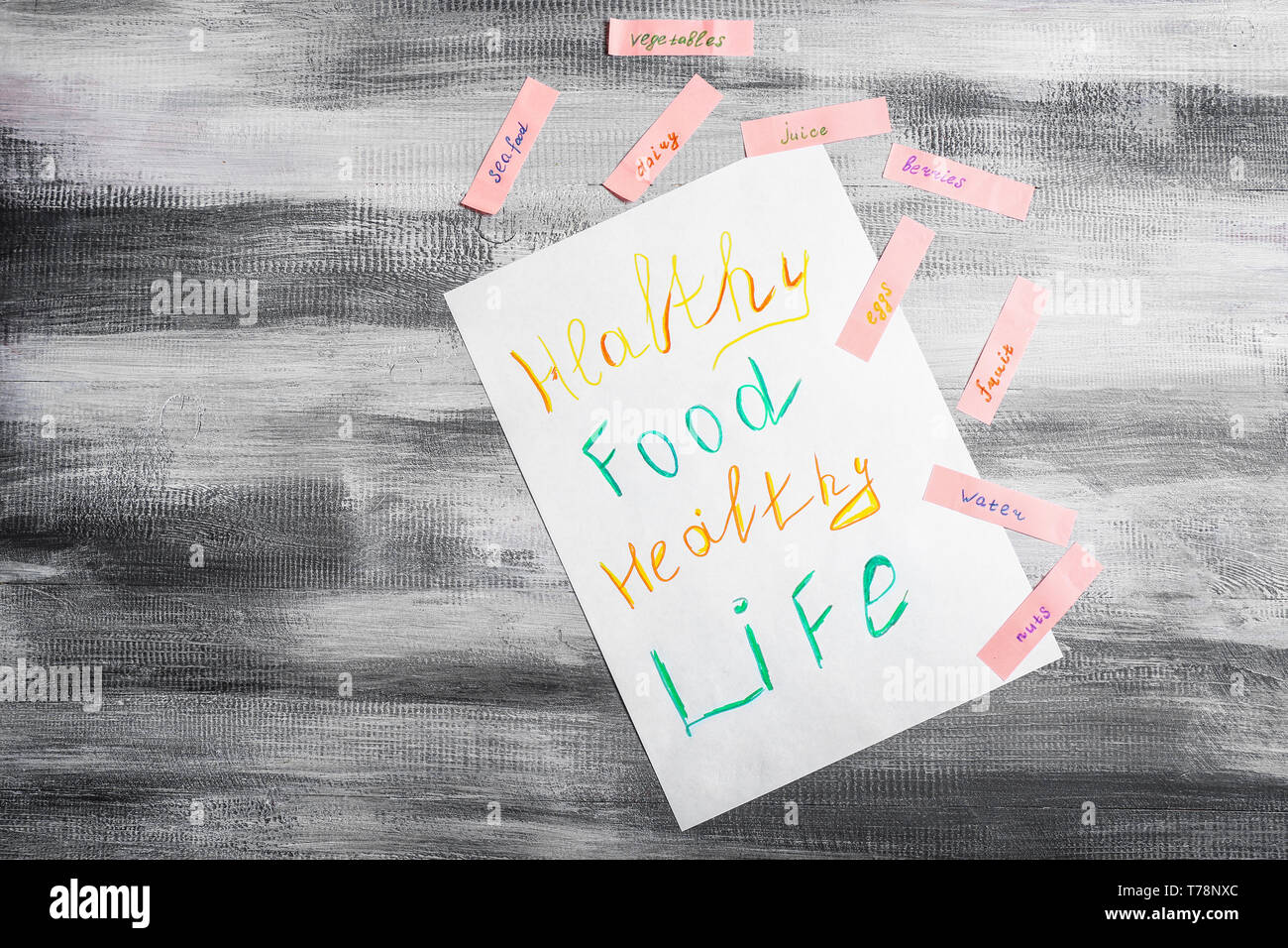 Sheet of paper with words "Healthy food - healthy life" on wooden table ...