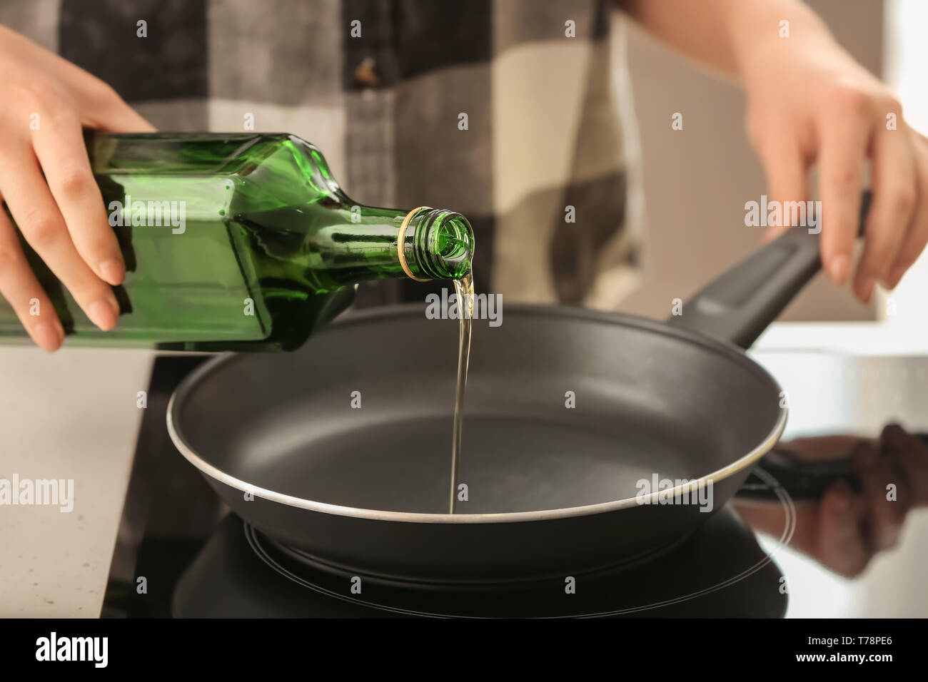 Woman pouring olive oil into frying pan on stove Stock Photo - Alamy