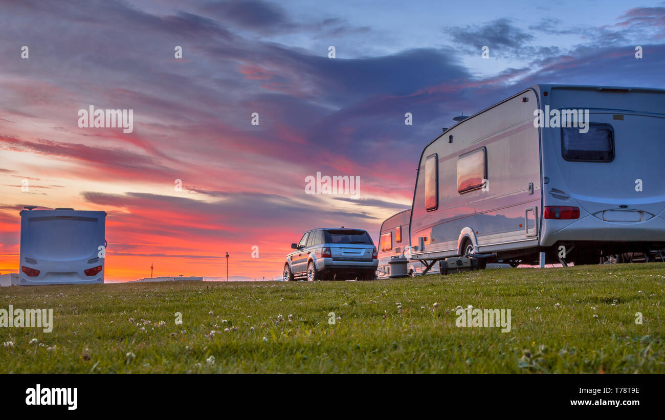 Camping caravans and cars parked on a grassy campground under beautiful ...