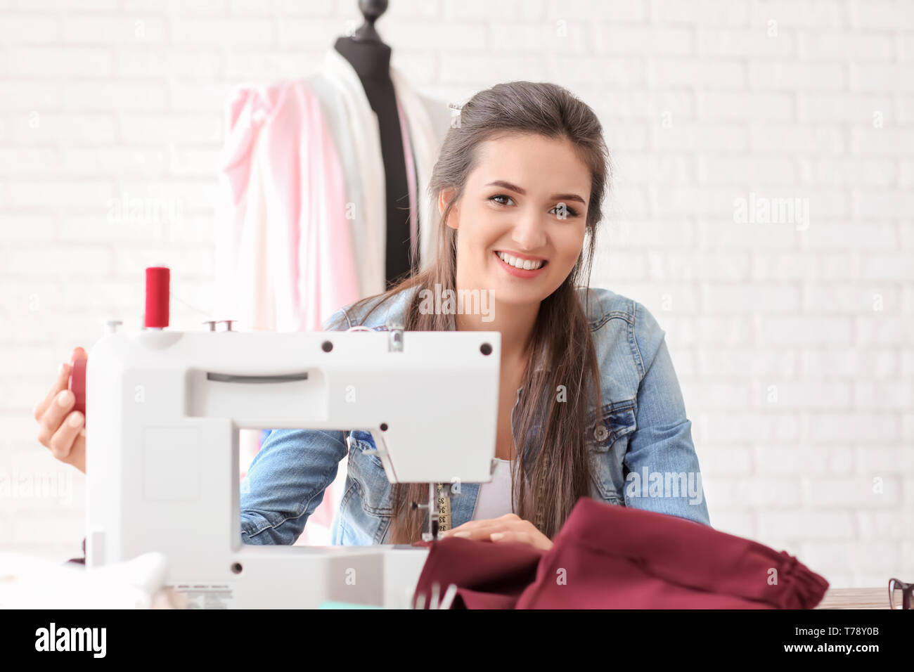 Young female tailor using sewing machine in atelier Stock Photo - Alamy