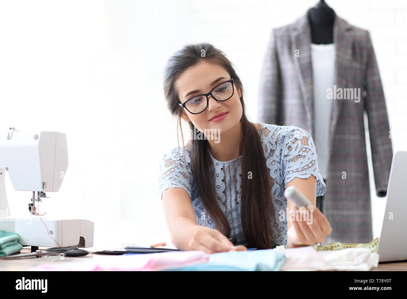 Young female tailor working at table in atelier Stock Photo - Alamy