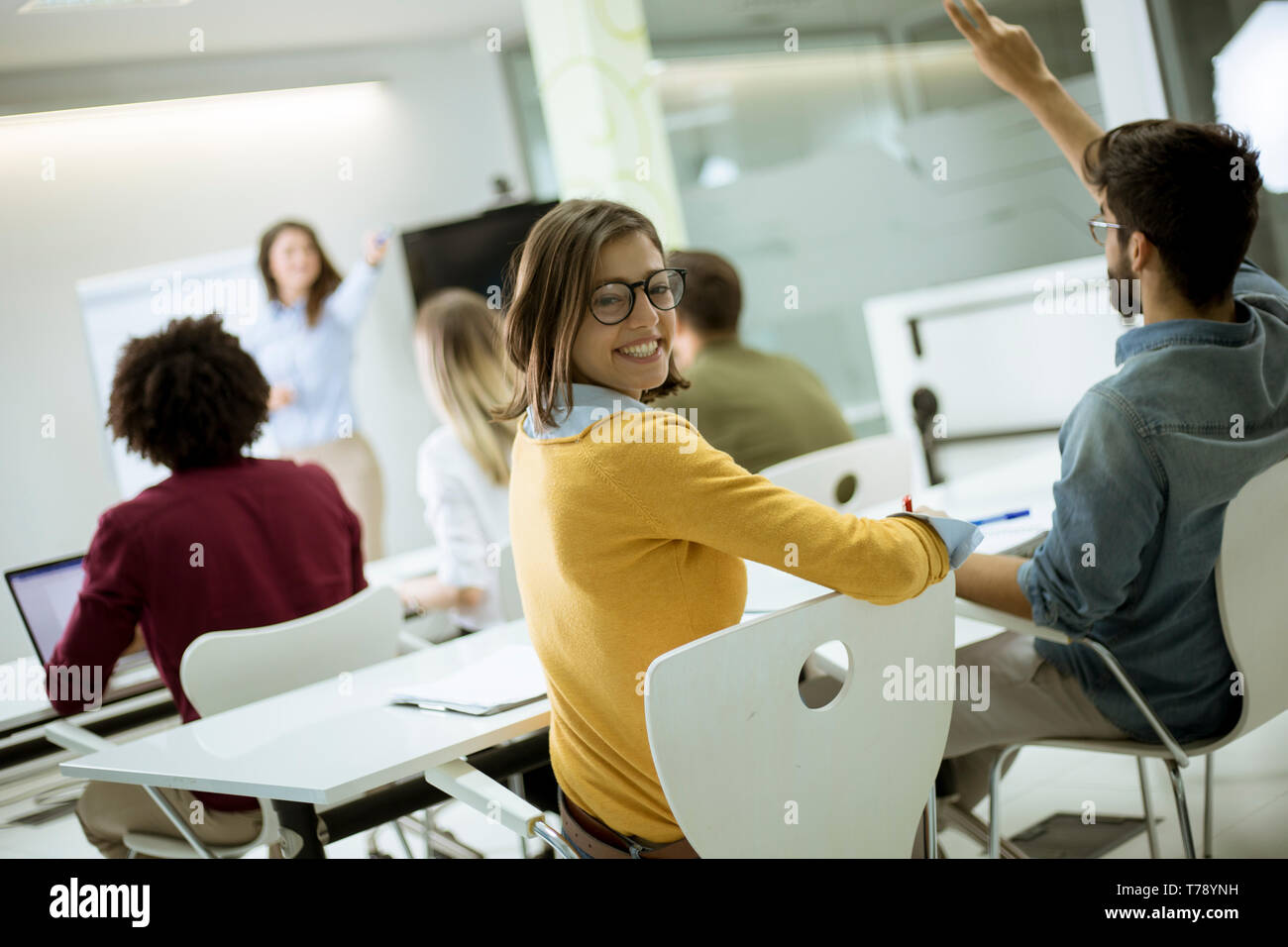 Group of young students rising hands to answer the question during the ...