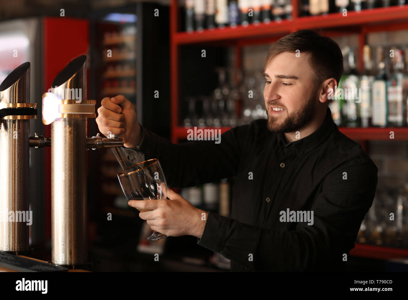 Bartender pouring beer into glass in bar Stock Photo - Alamy
