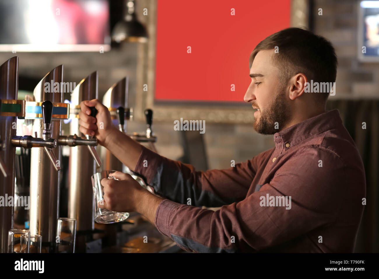 Bartender pouring beer into glass in bar Stock Photo - Alamy