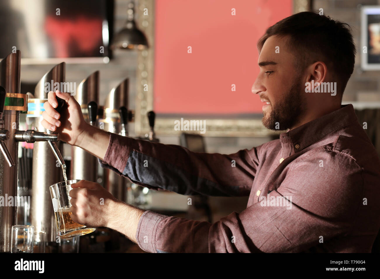Bartender pouring beer into glass in bar Stock Photo - Alamy
