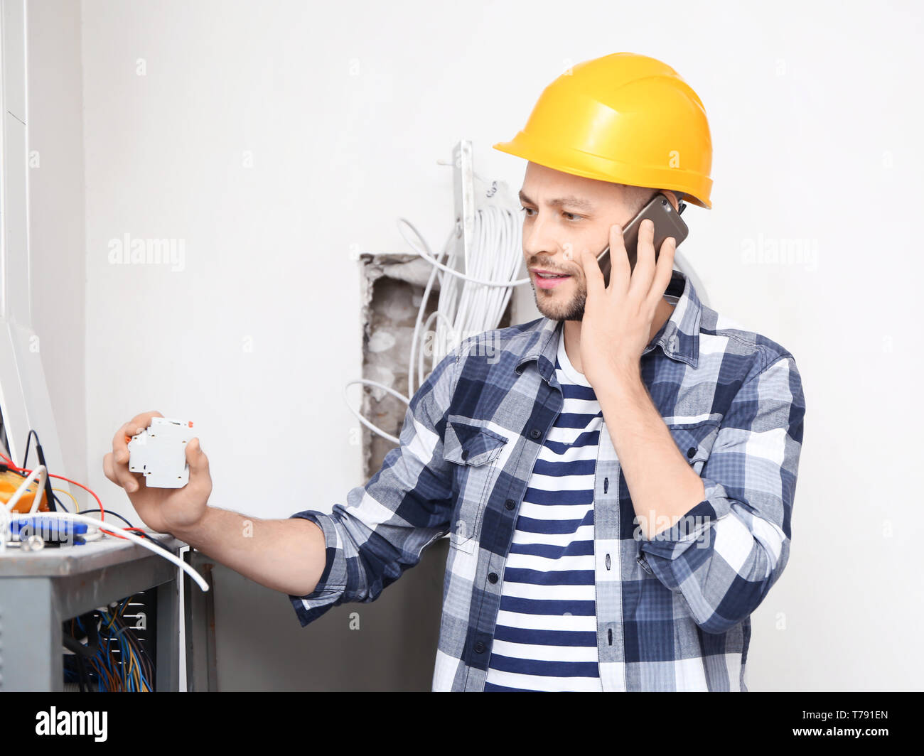 Electrician talking on phone near distribution board indoors Stock ...