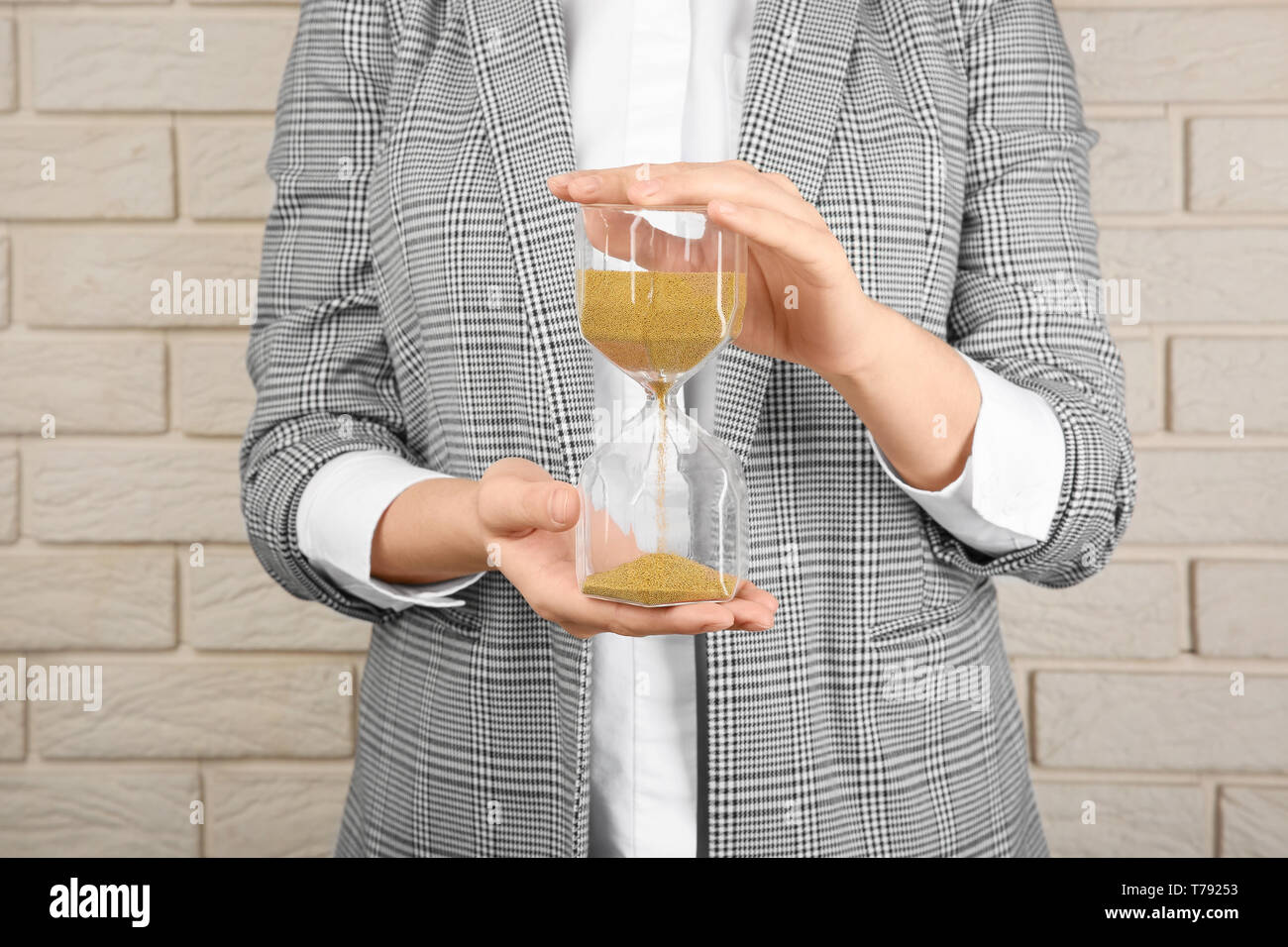 Woman holding hourglass near brick wall. Time management concept Stock ...
