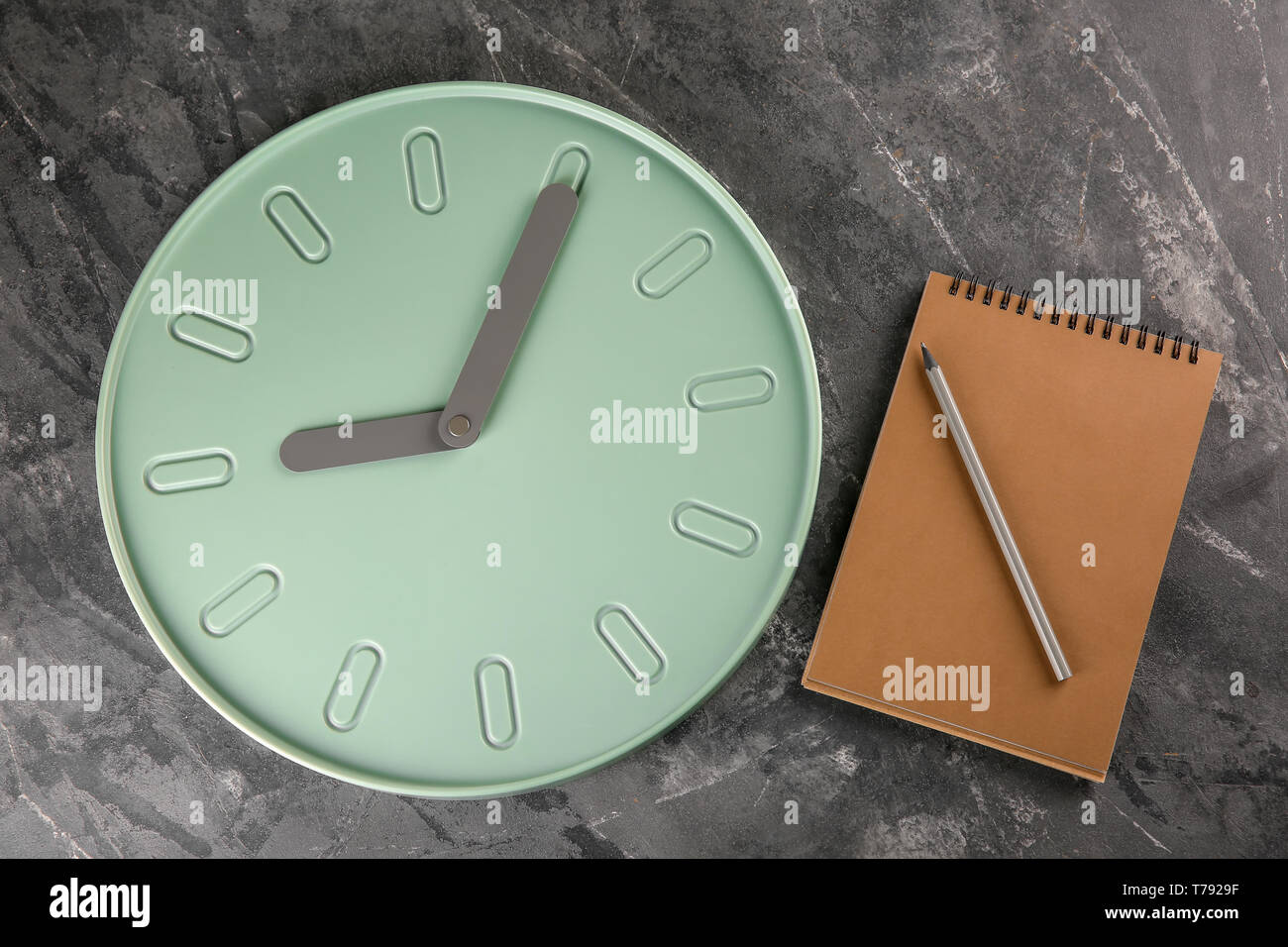 Clock with notebook and pencil on grey textured background. Time ...