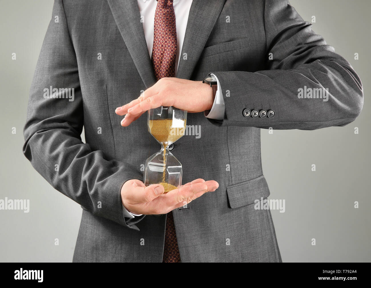 Man holding hourglass on grey background. Time management concept Stock ...