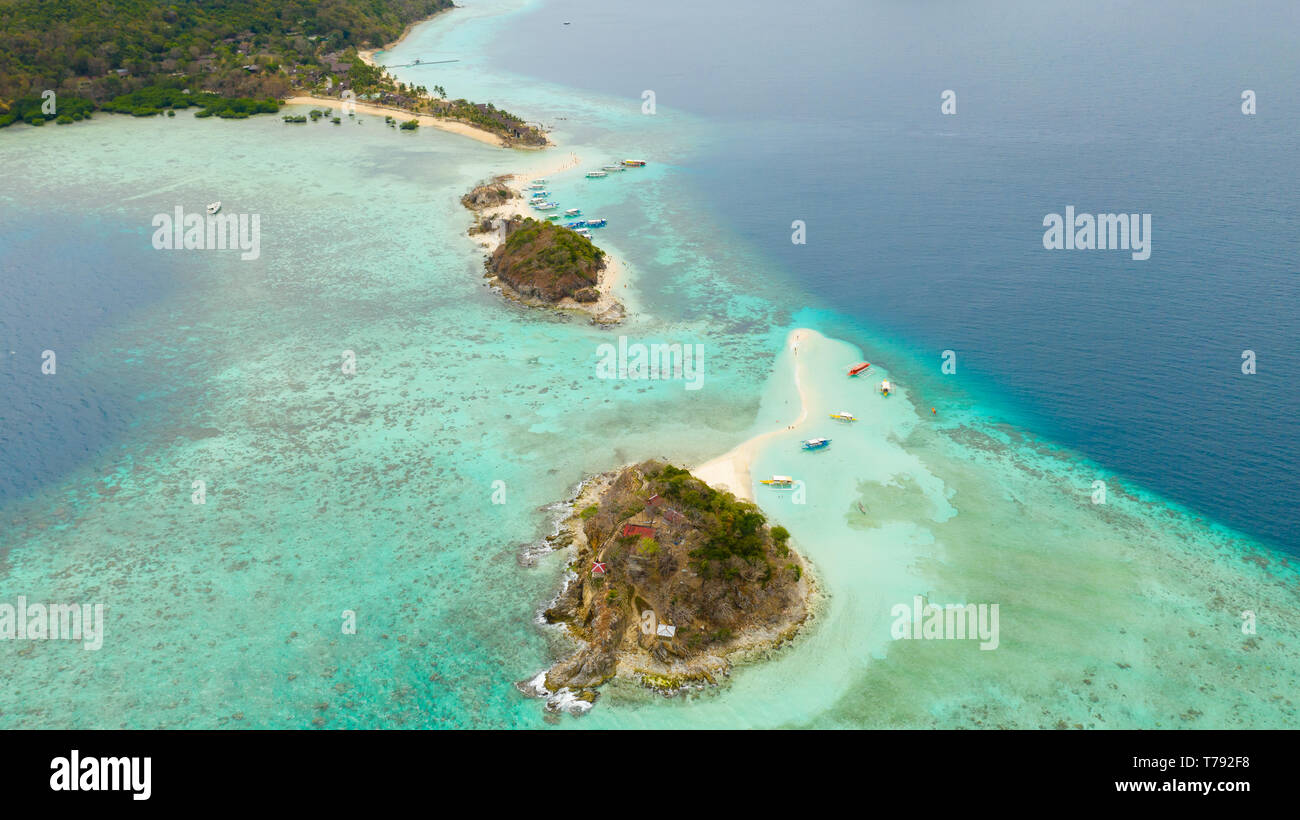 Island with a sand spit and coral reefs. Clear transparent sea near the ...