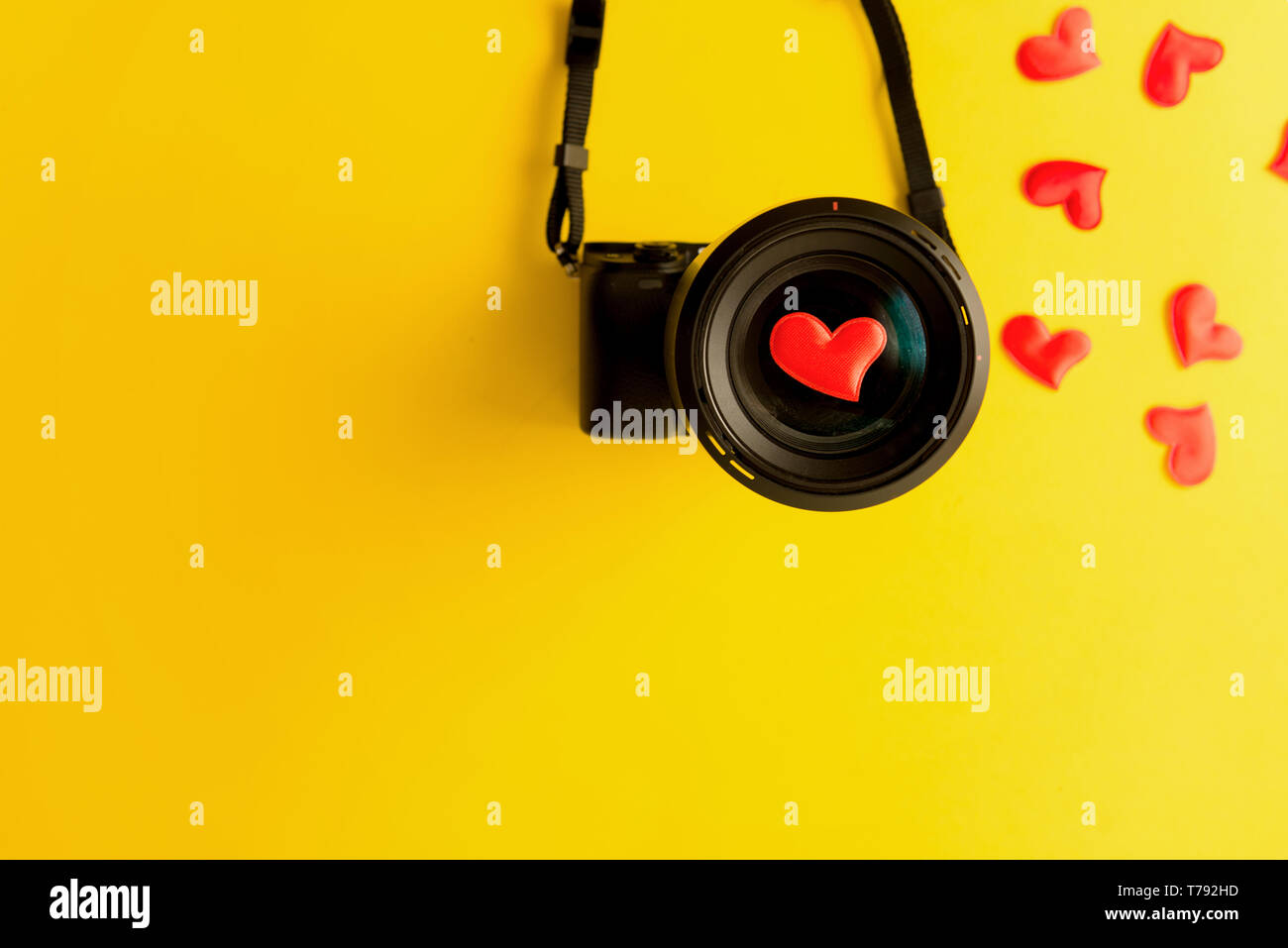 Flat lay of mirorless camera with lens and love red hearts on yellow ...