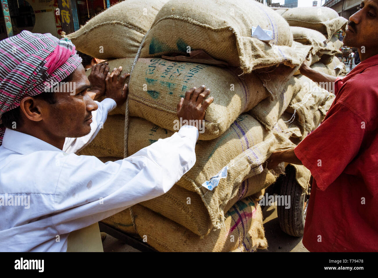 Dhaka, Bangladesh : A man pushes a cart loaded with sacks full of rice ...