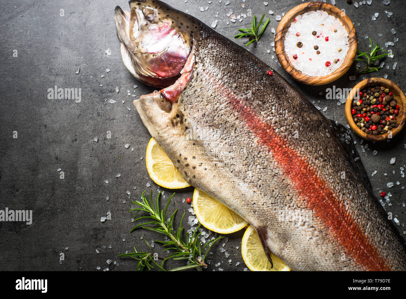 Raw salmon fish whole with ingredients for cookings on black Stock ...