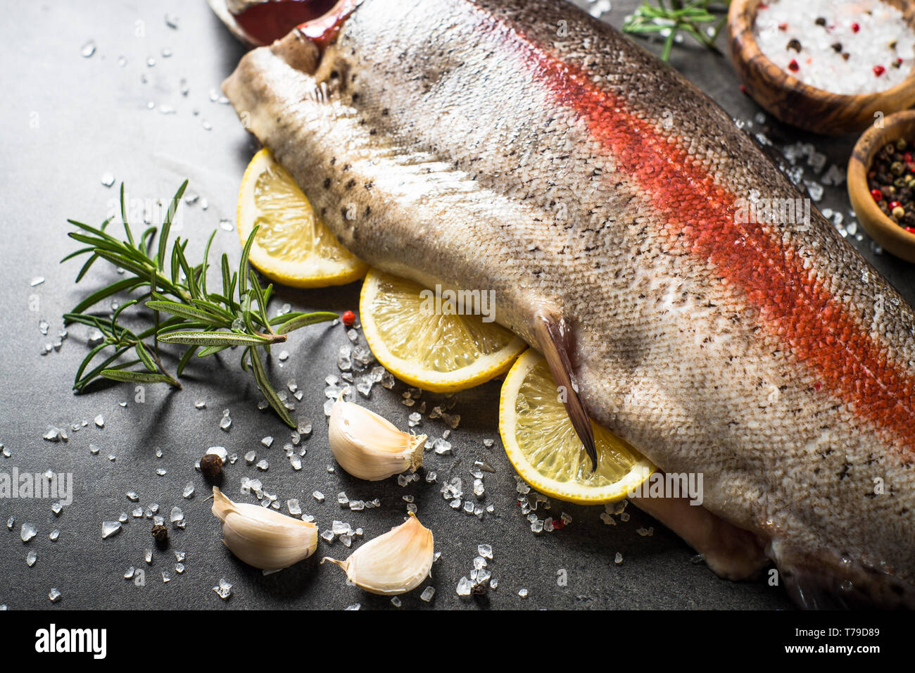 Raw salmon fish whole with ingredients for cookings on black Stock ...
