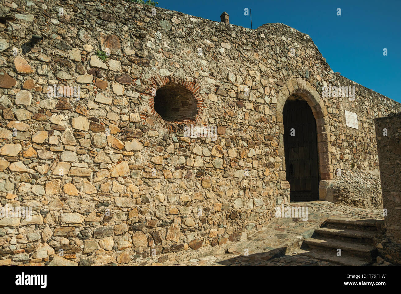 Close-up of gateway with wooden door in the stone outer wall and ...