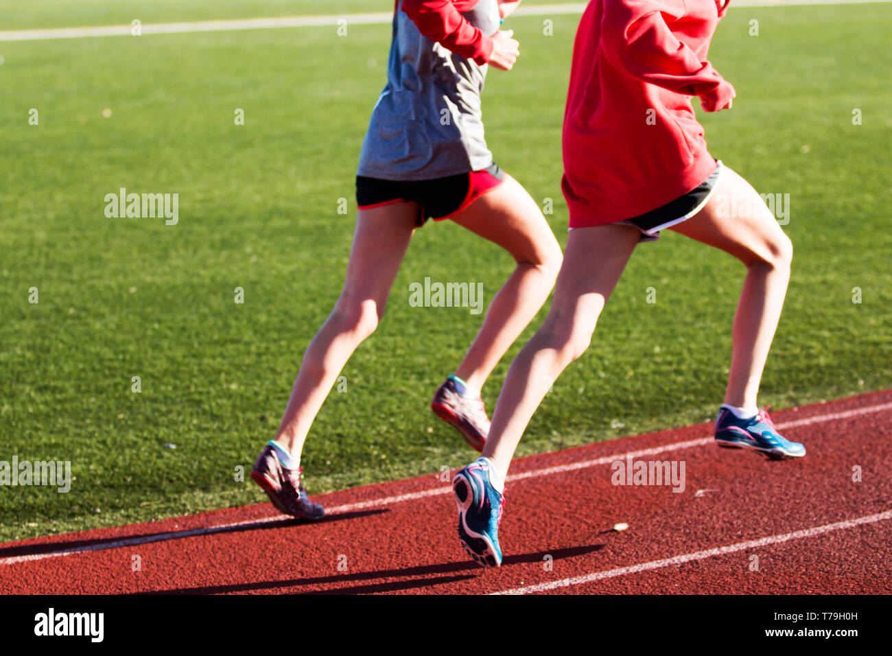Two girls training for speed together on a red track Stock Photo - Alamy