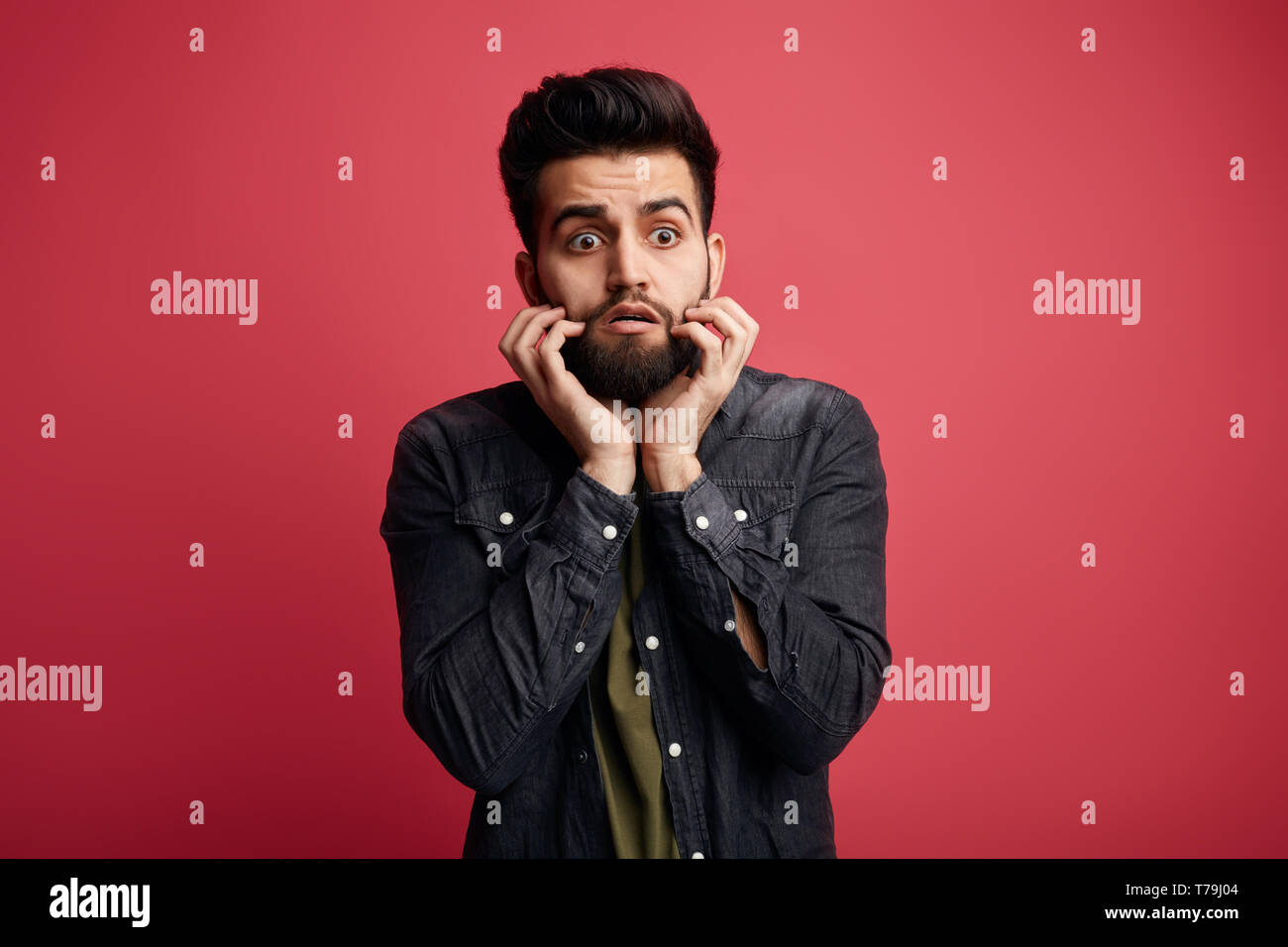 handsome scared man with fingers on his mouth, being afraid of ...