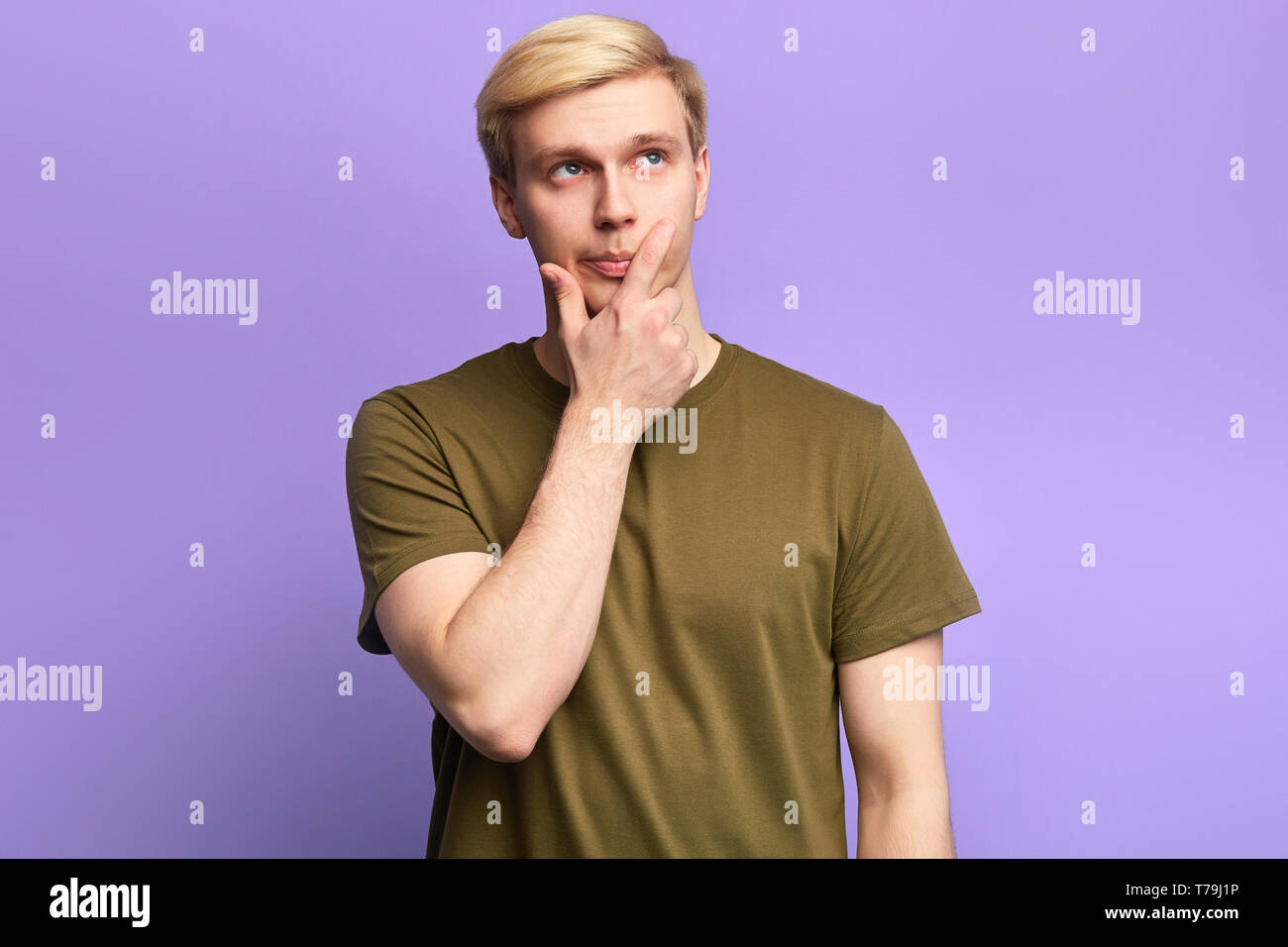 Handsome serious puzzled young man looking up with thoughtful and ...