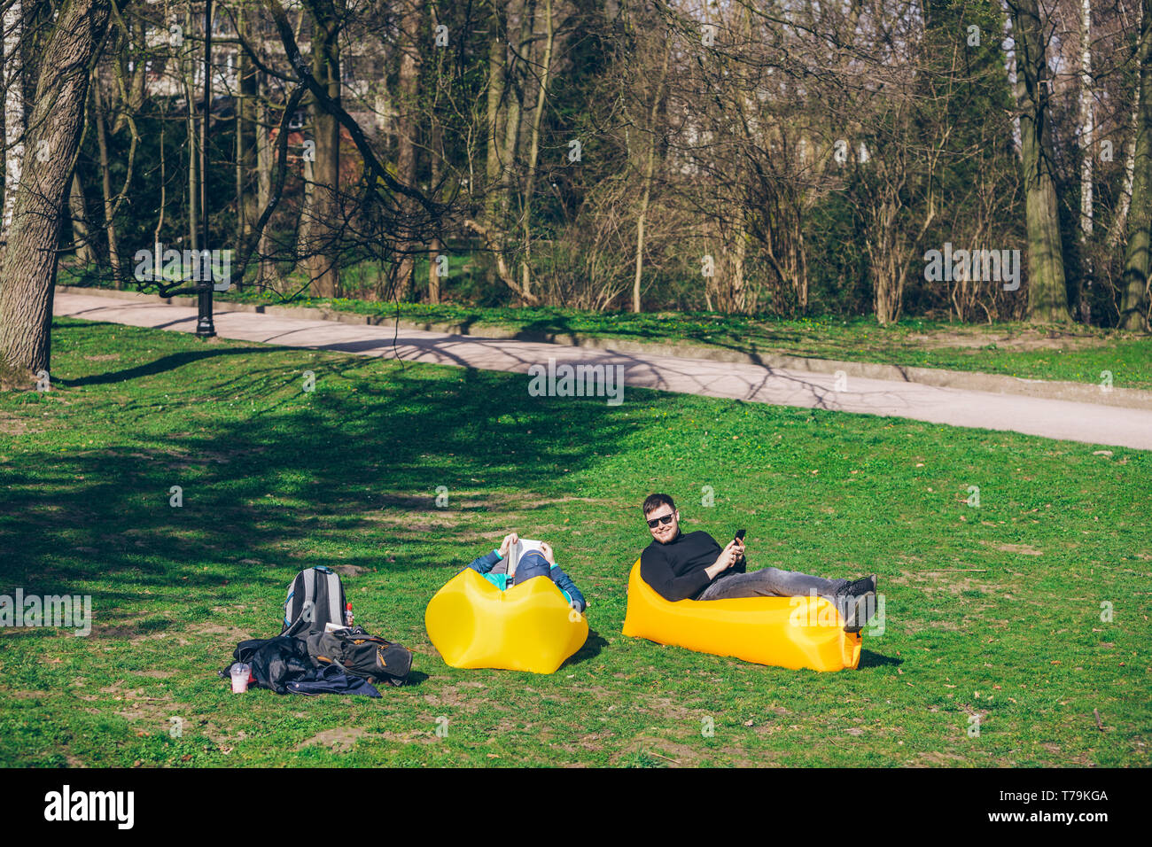 two men friends laying on yellow inflatable mattress reading books ...