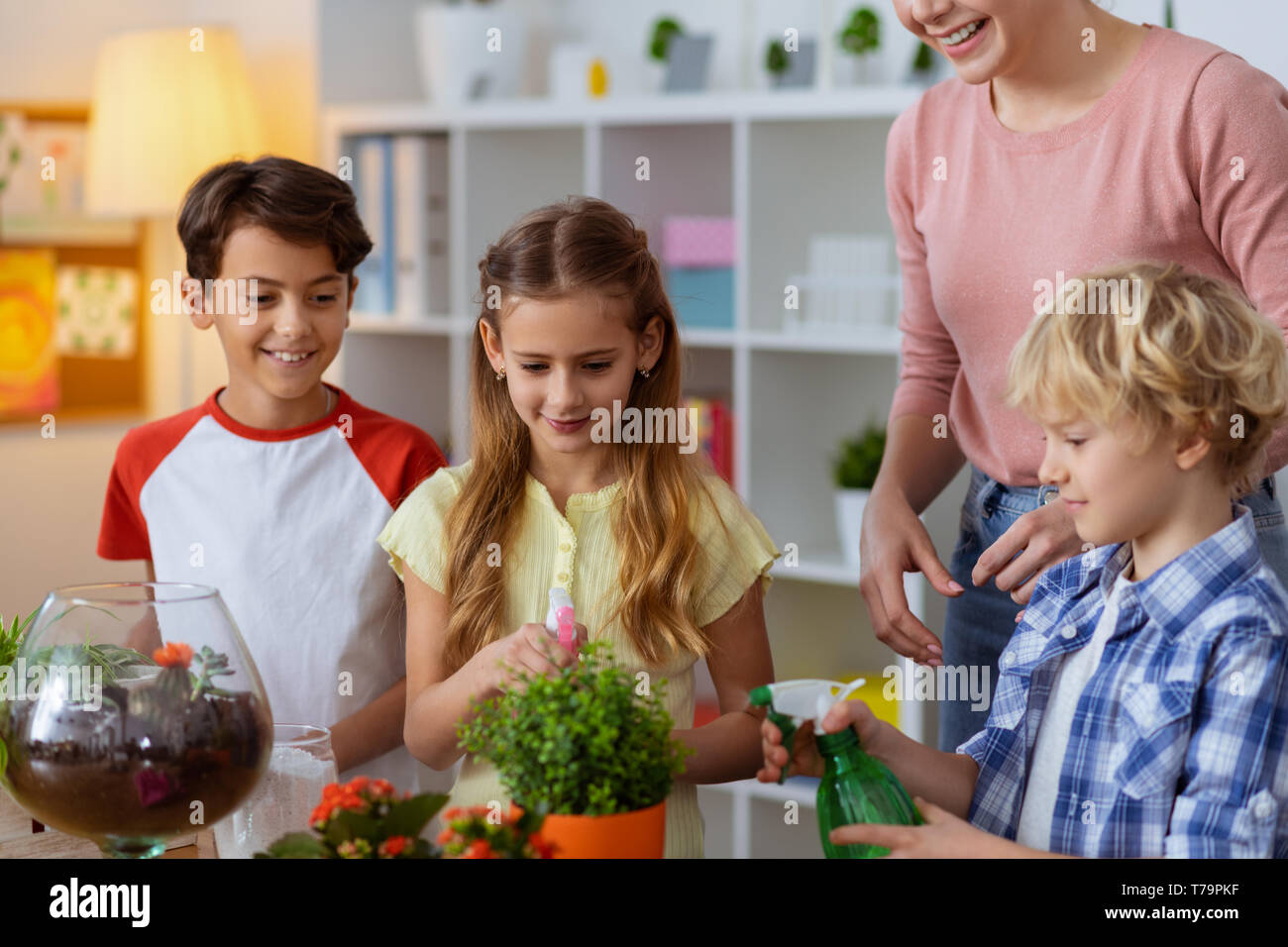 Involved pupils. Three pupils feeling involved in watering plants with ...
